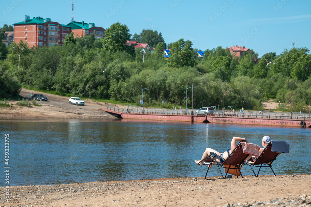People sunbathe on the beach of the city river. Rest on the river ...