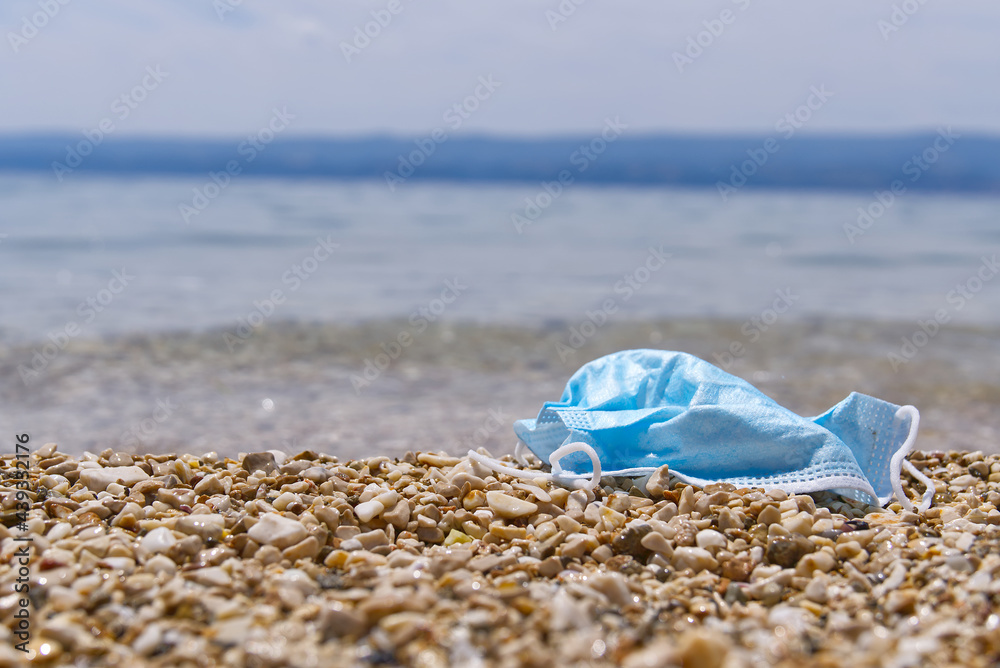 Used blue medical face mask lies on the beach. Environmental and coast ...