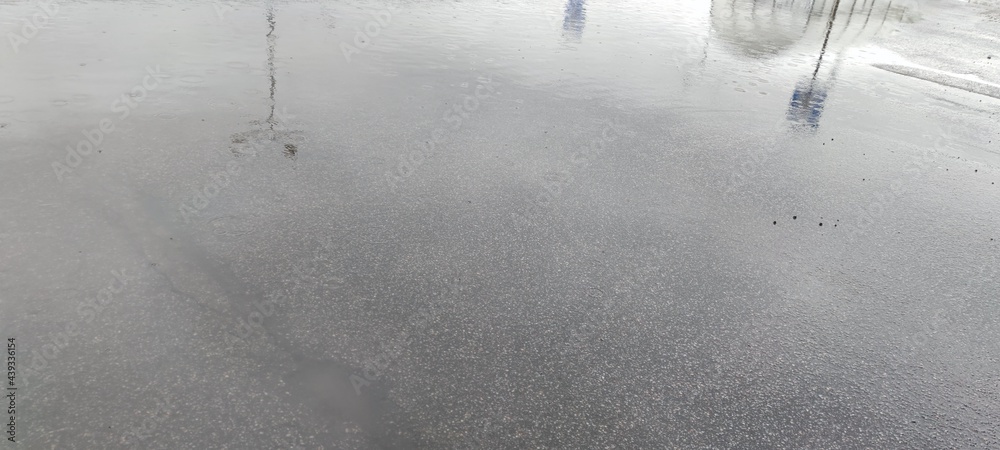 A large puddle of water on the asphalt. A wide and deep pool of dark ...