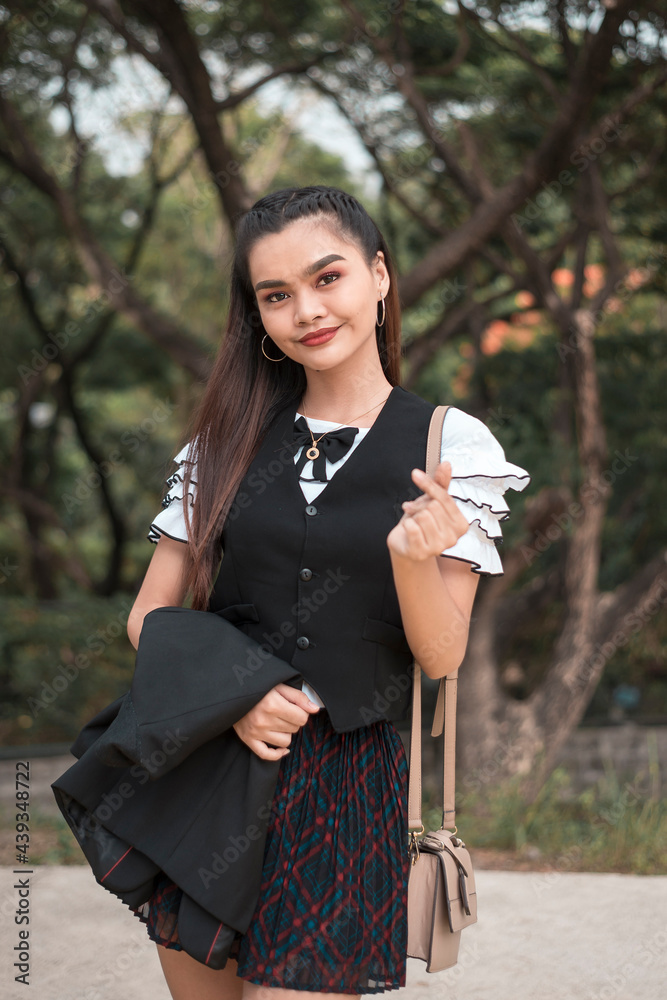 A gorgeous, tall and beautiful senior high school student doing a heart ...