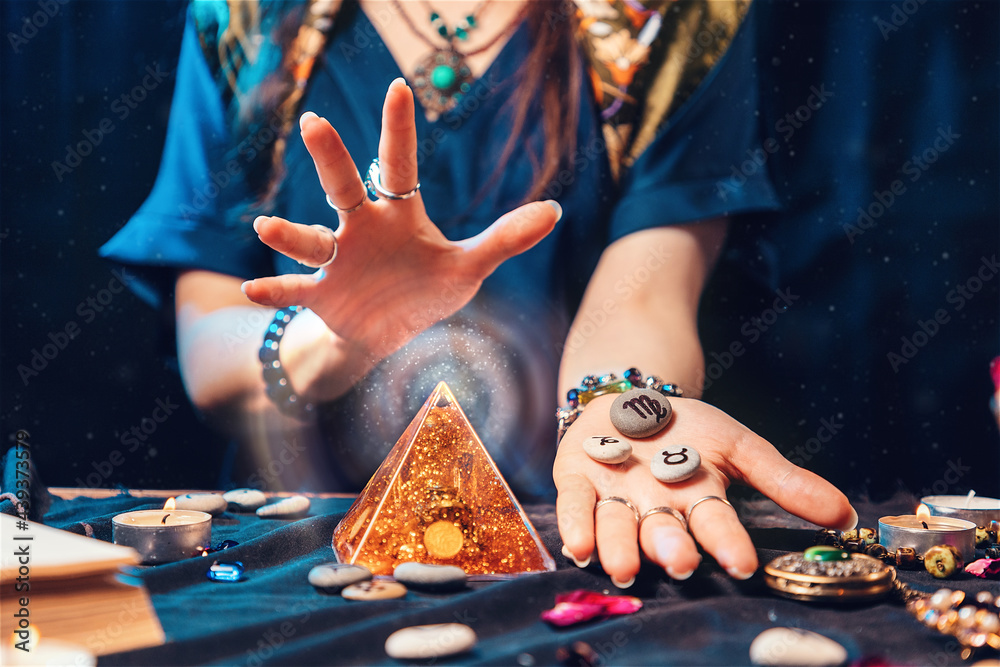 Astrology and magic. A fortune teller holds stones with the sign of the ...