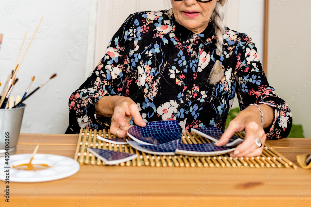 Portrait of hoary woman repairing a broken plate with a millenial ...