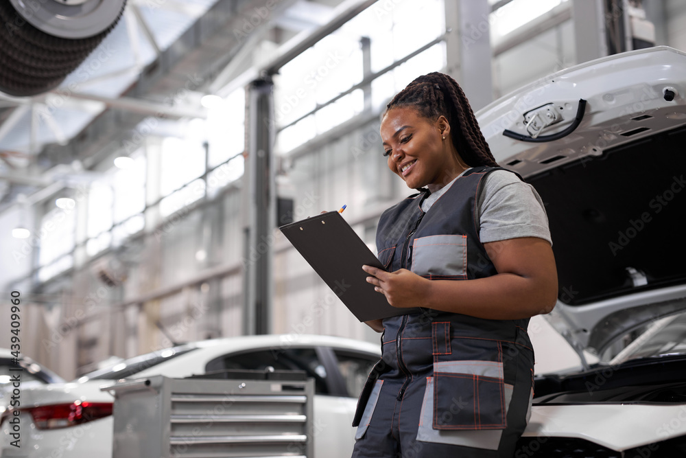 black female Auto Mechanic Making Car Checkup, in Uniform Writing and ...