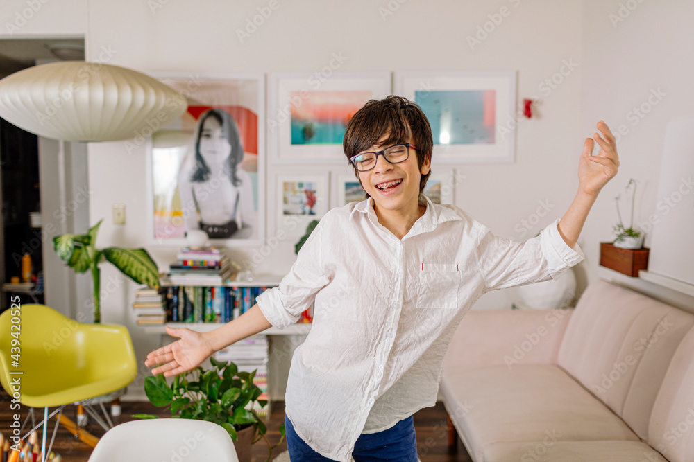 Happy Pre-teen with braces dancing in colorful room by bookshelves and ...