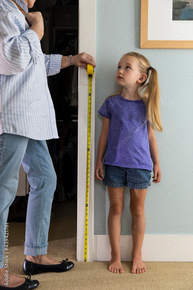 Smiling Girl Measuring her height Stock Photo | Adobe Stock