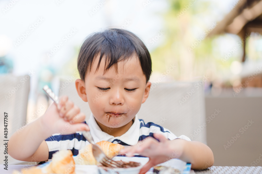 Asian toddler boy eating croissant with chocolate lunch in the school ...