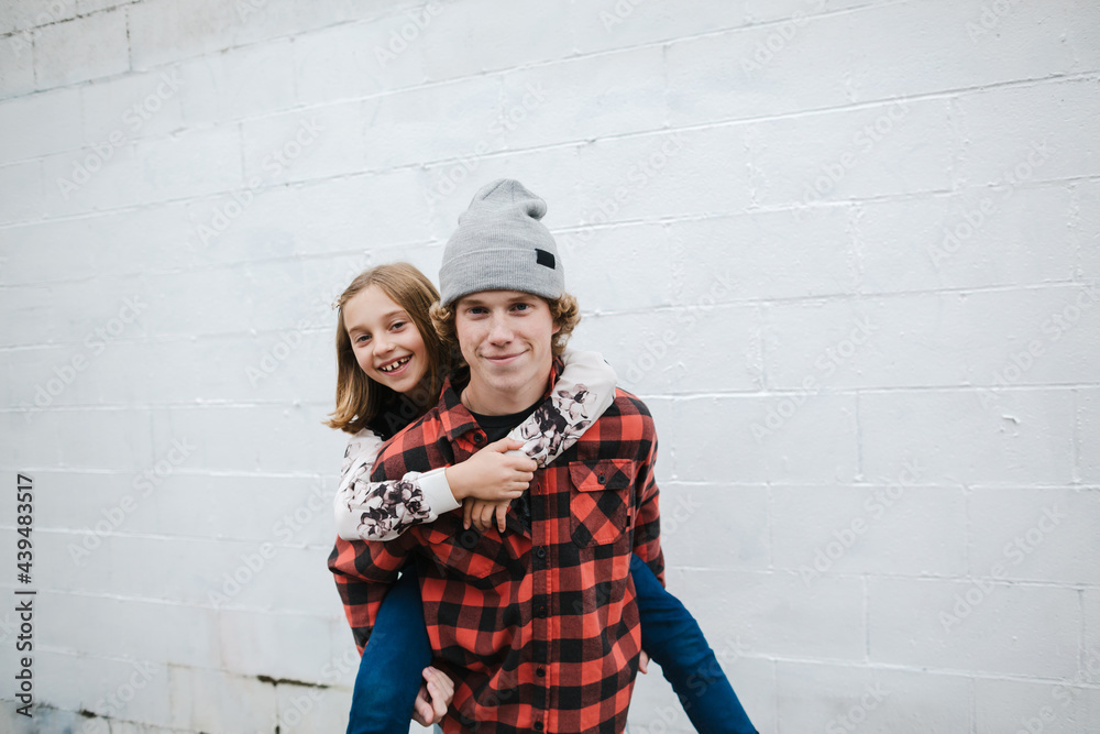 Teenage boy giving young girl piggyback ride Stock Photo | Adobe Stock