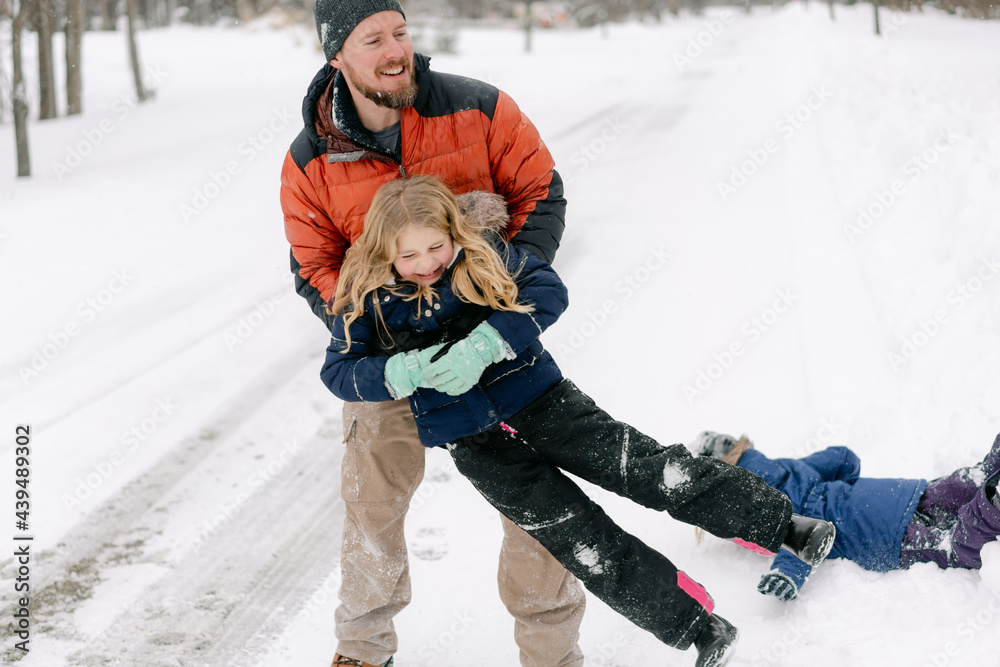 dad throwing his girls in a snow piles Stock Photo | Adobe Stock
