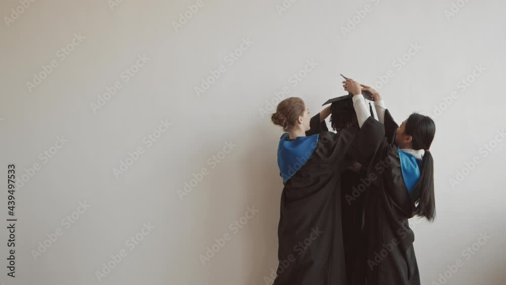 Wide medium shot with slowmo of three multi-ethnic young graduate ...