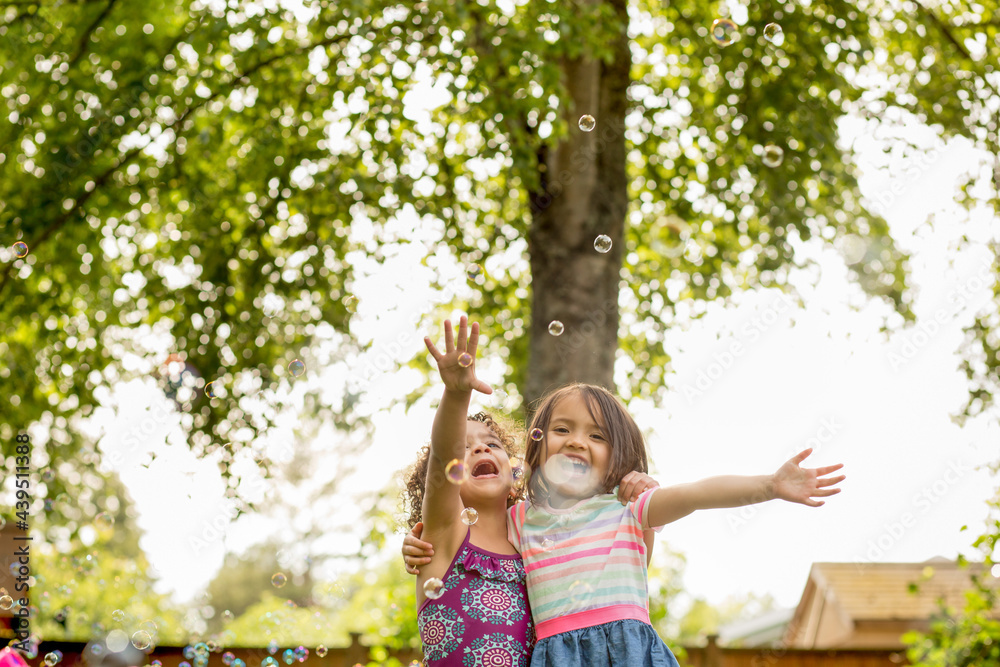 Excited friends hug and grab at bubbles Stock Photo | Adobe Stock