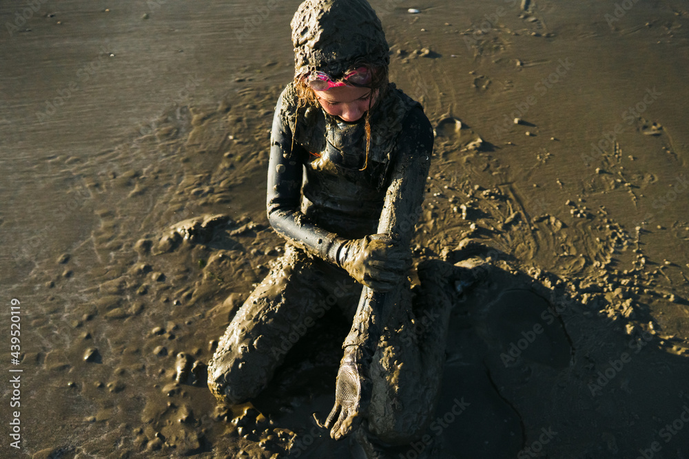 Girl in wetsuit covered in sand Stock Photo | Adobe Stock