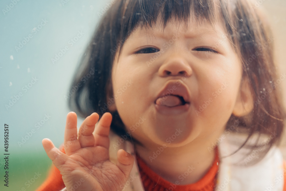 Portrait of cute little girl behind glass Stock Photo | Adobe Stock