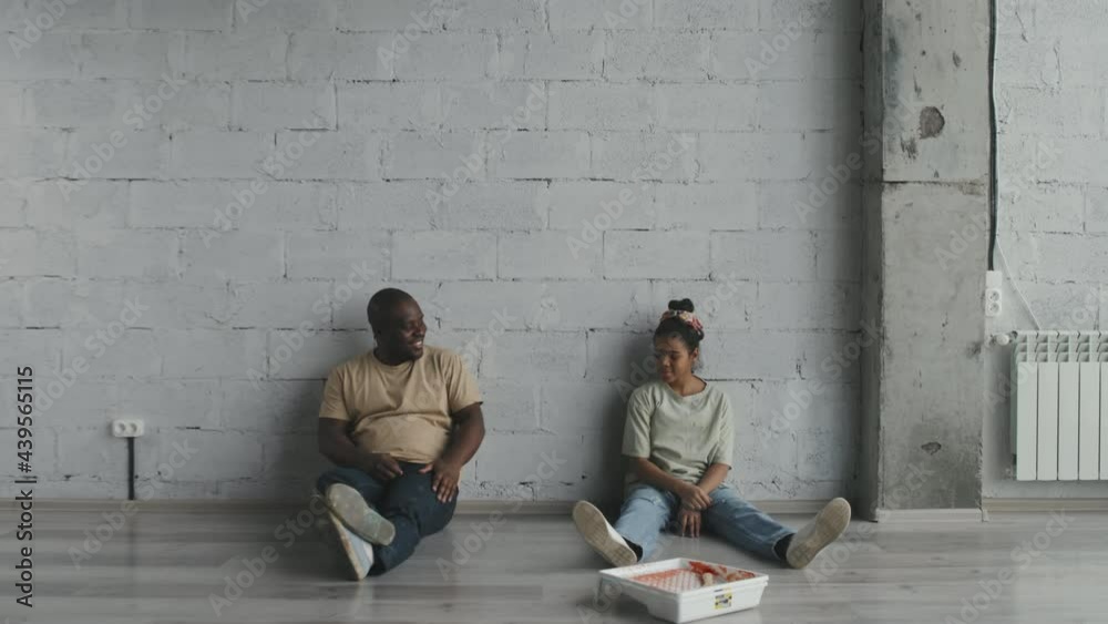 Wide shot of cheerful African-American father and daughter sitting ...