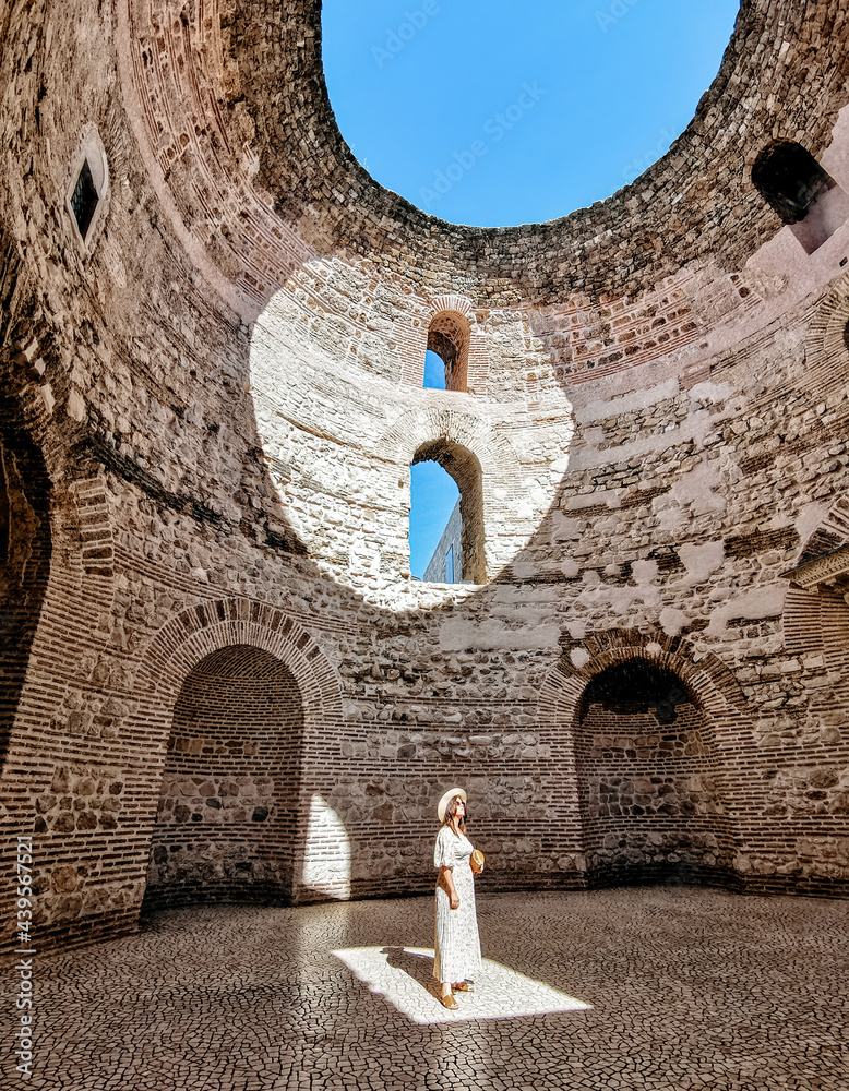 Woman standing inside ancient roman building with natural light shining ...