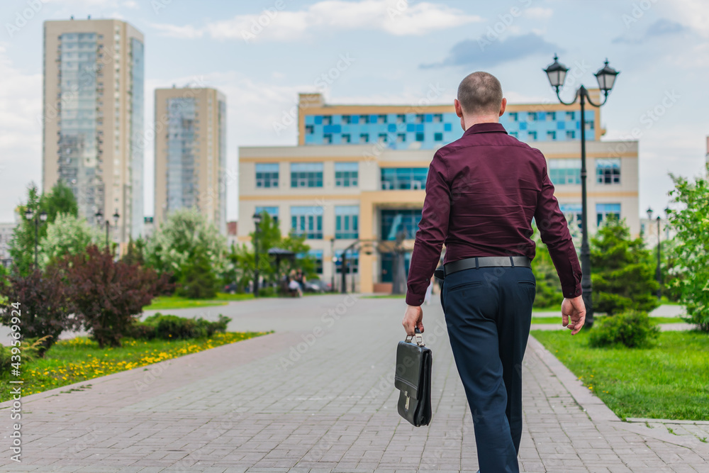 A man with a briefcase going to work in an office building. Back view ...