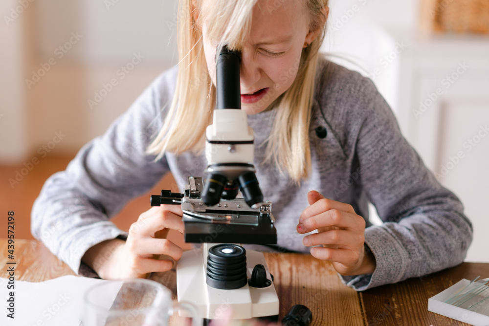 young girl looking through microscope Stock Photo | Adobe Stock