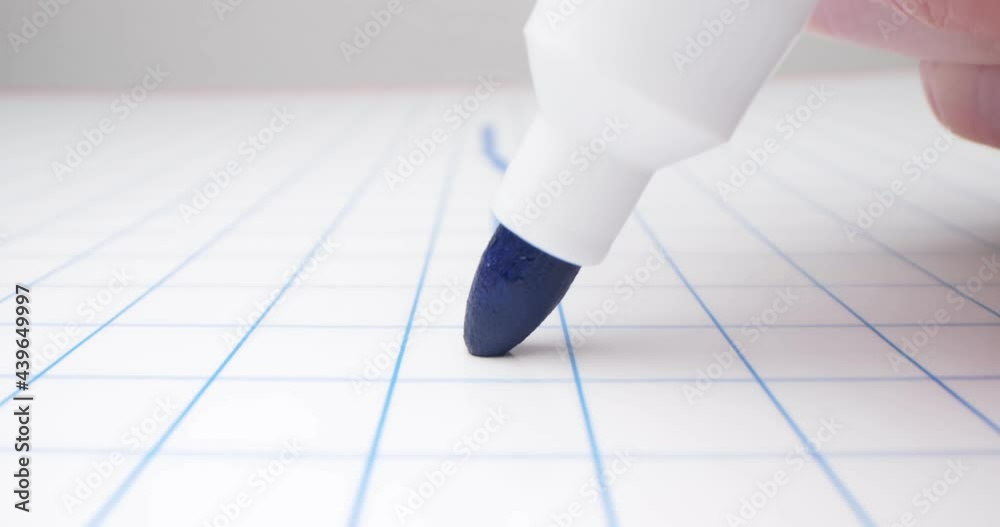 detailed extreme close-up blue felt-tip pen draw a line on a checkered ...