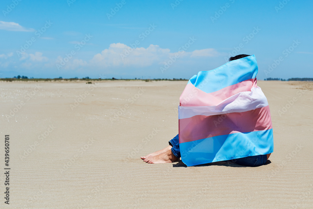 young person wrapped in a transgender pride flag Stock Photo | Adobe Stock
