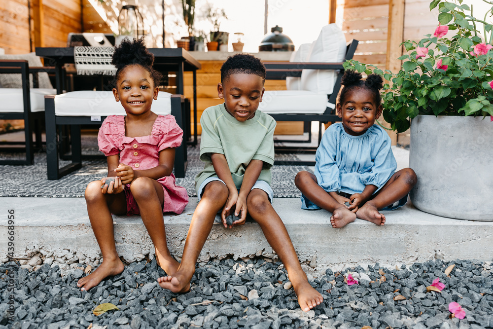 Three kids playing outside in the backyard sitting on the patio. foto ...