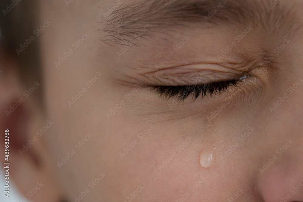 Teardrop is rolling down on childs face, expression of unhappy emotions ...