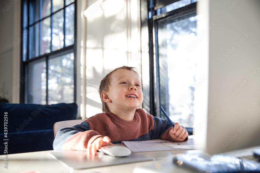 Little boy smiling while using desktop computer Stock Photo | Adobe Stock