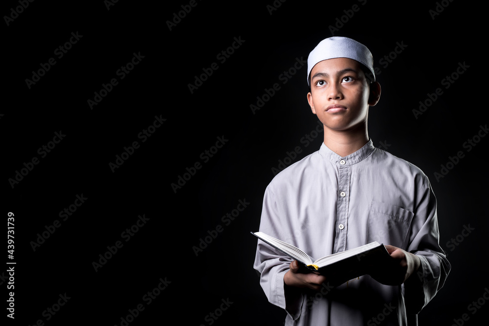 Portrait A Muslim boy in Asian Islam is standing and reading the Quran ...