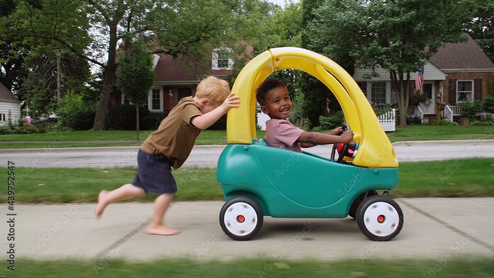 Caucasian boy pushing an African American boy in a toy car Stock Photo ...
