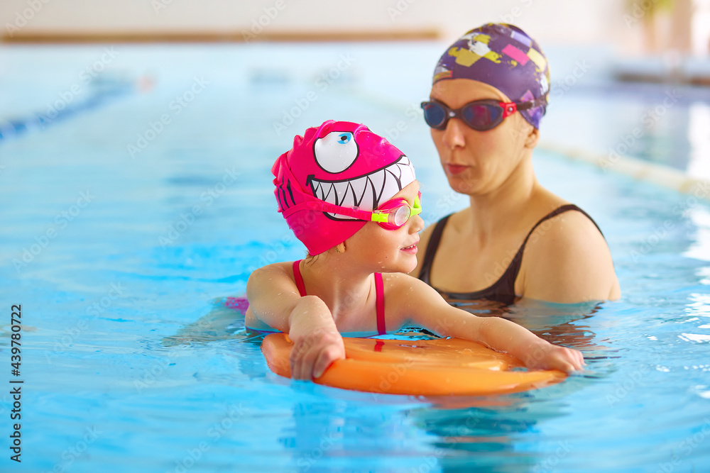 Portrait of mother or coach learning to swim with flutter board little ...
