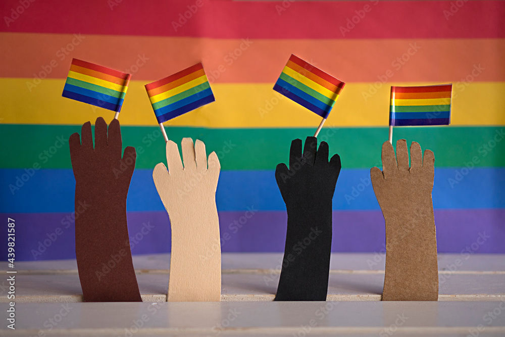 Four multiracial hands holding LGBTQIA flags in front of a rainbow ...