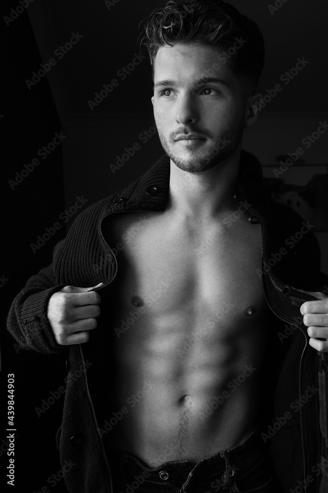 Portrait of handsome man with beard standing next to window with open ...