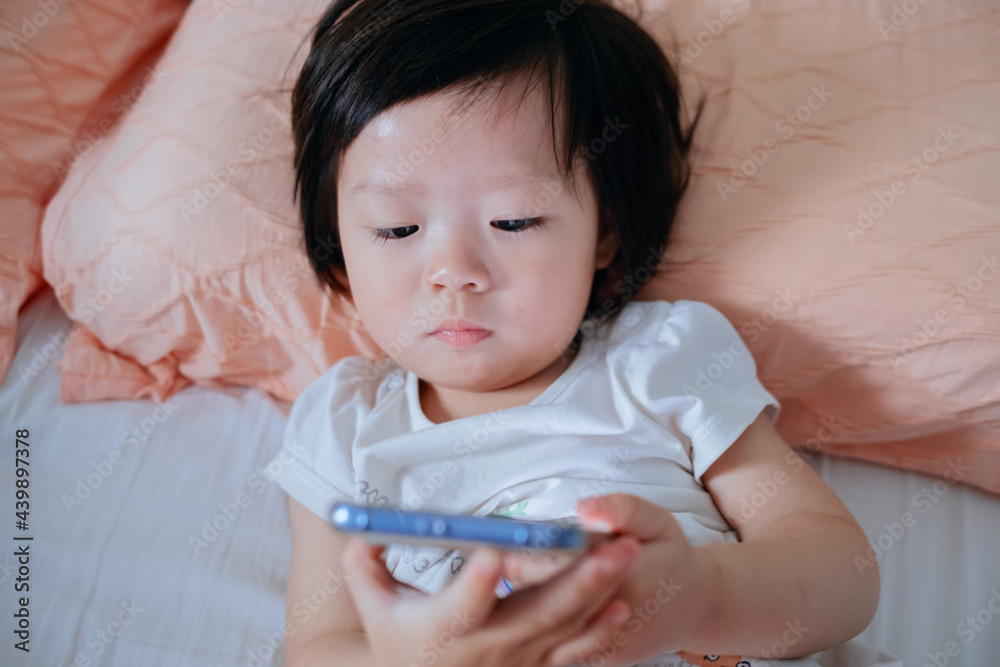 little girl lying on bed using mobile phone Stock Photo | Adobe Stock