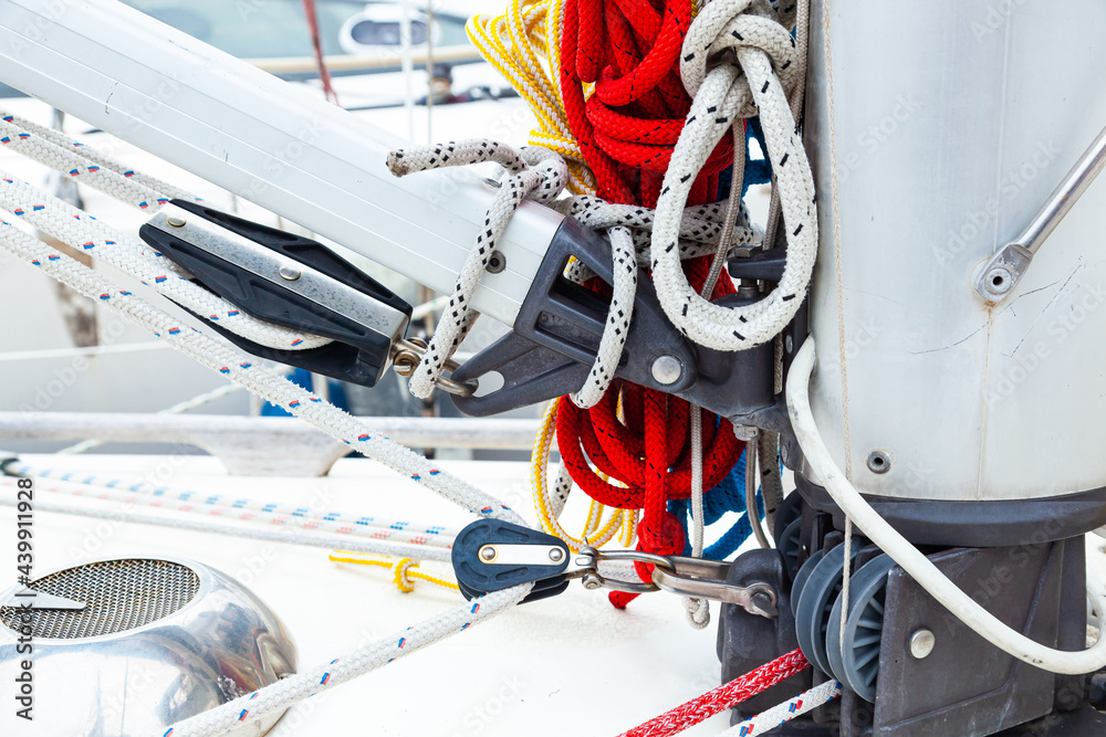 Part of the mast and hull of a sailing yacht, with multi-colored ropes ...