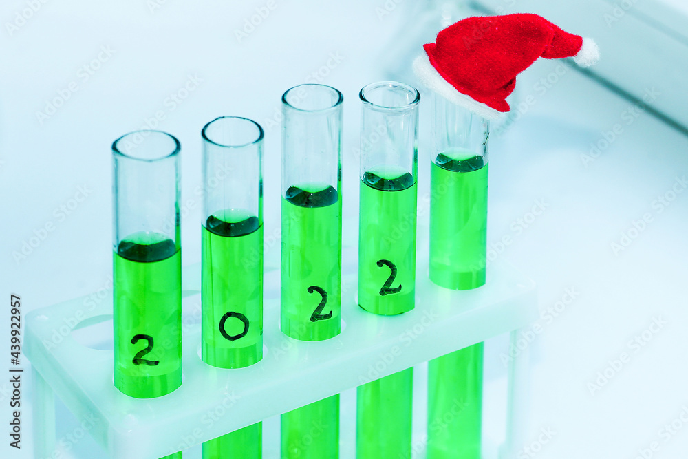 five vials of green solution in a chemical lab. on the end tube is a ...