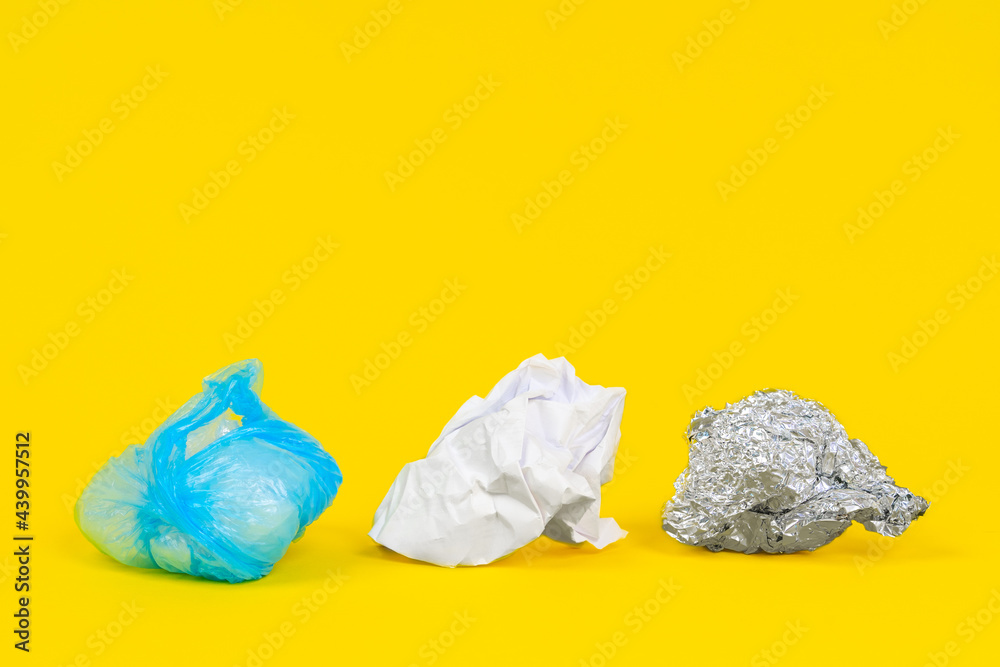 Crumpled paper, plastic, and foil lie in a row next to each other on ...