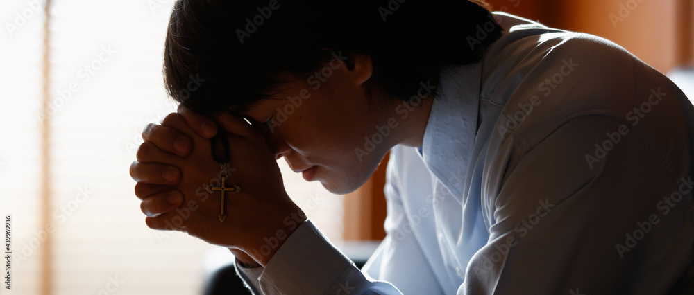 Asian man bowing his head on the Bible and carrying a cross. According ...