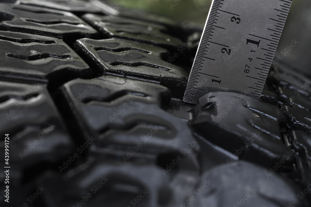 Car care staff using a steel ruler check and measurement tire tread ...