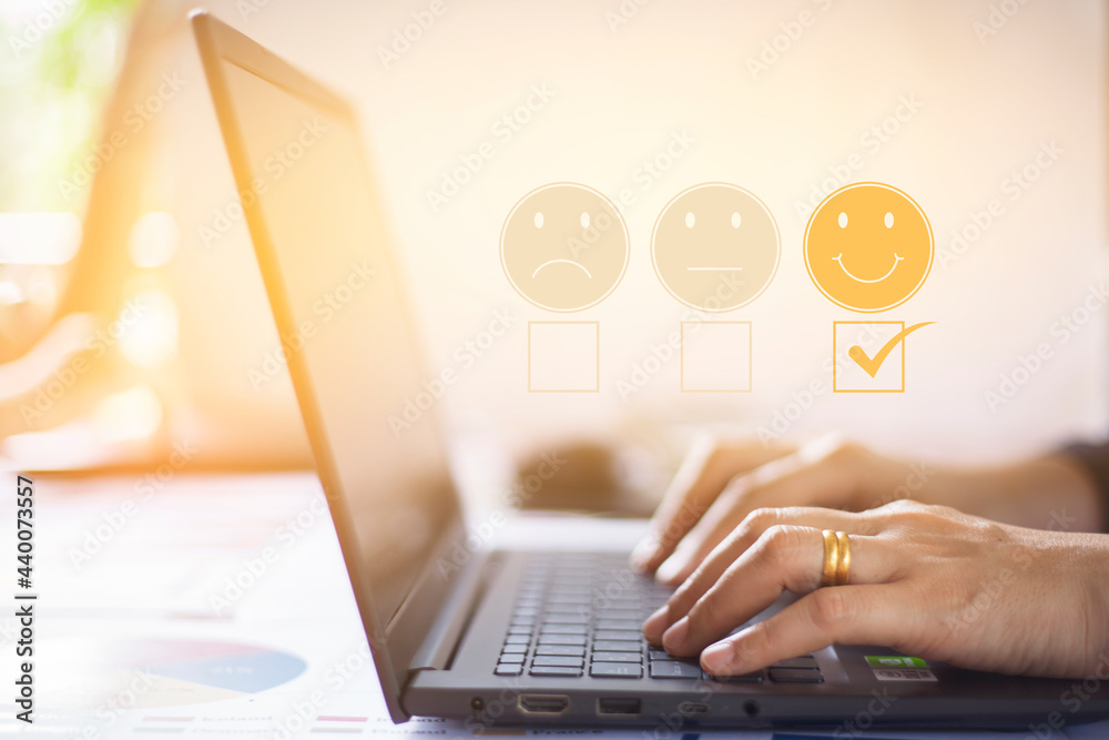 Smart woman using a laptop to choose a happy smiley face icon. Feedback ...