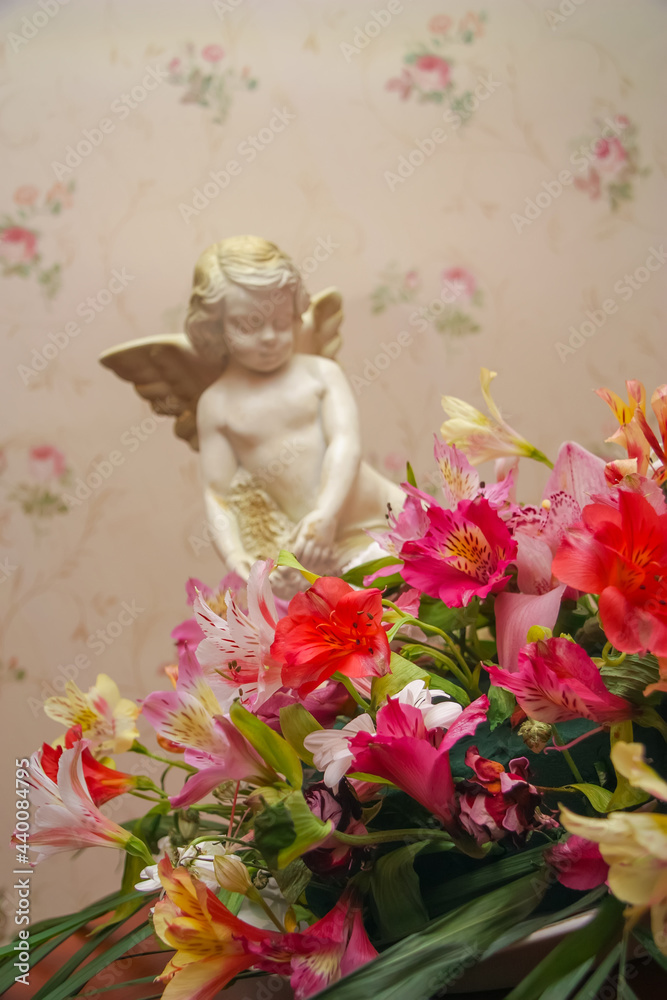 Lovely angel in flowers. Cherub sitting in the flowers of the daylily ...