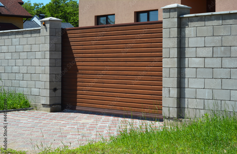 A close-up of a wood slat automatic sliding gate, entrance driveway ...