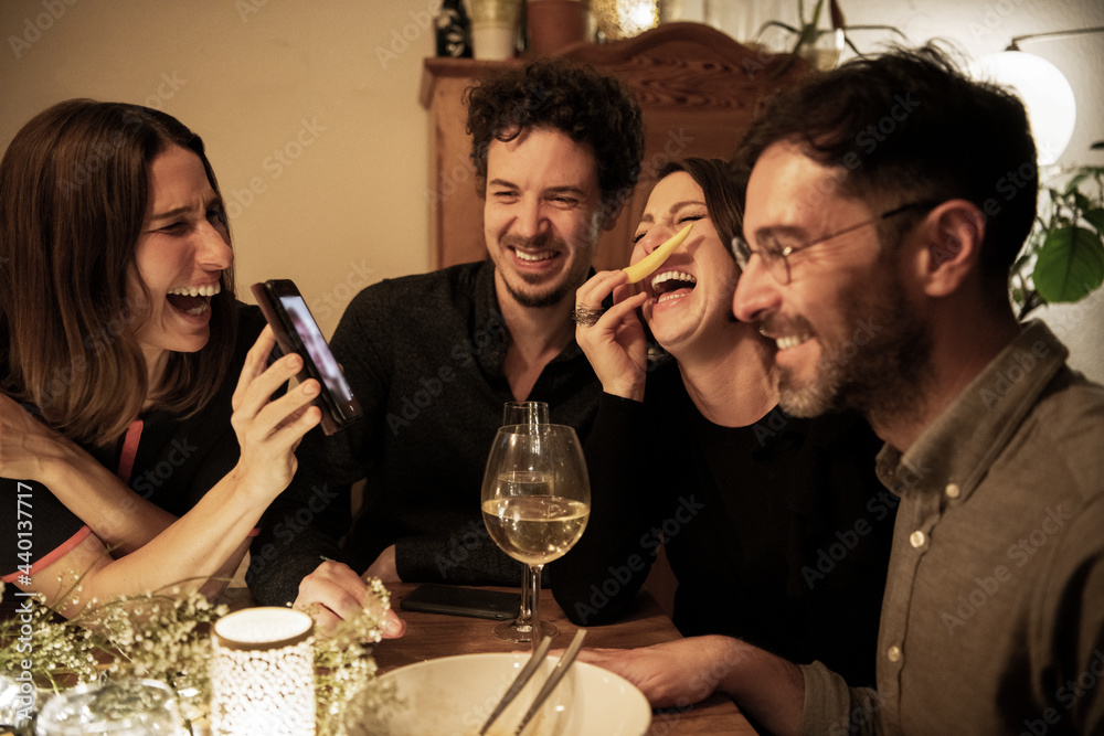 Female friends laughing during video call through mobile phone at home ...
