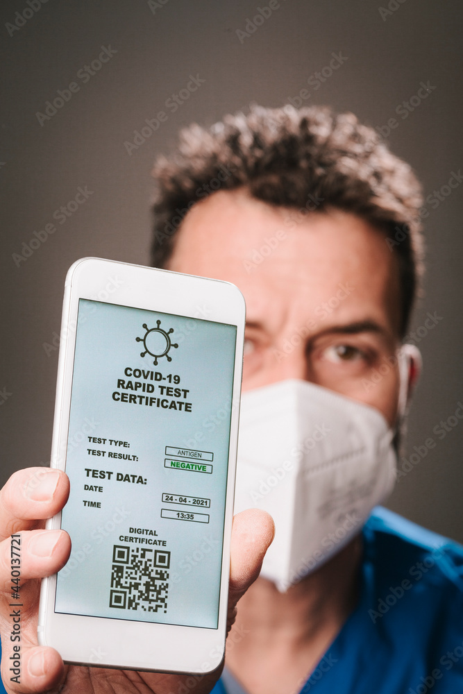 Male healthcare worker with face mask showing rapid test certificate on ...