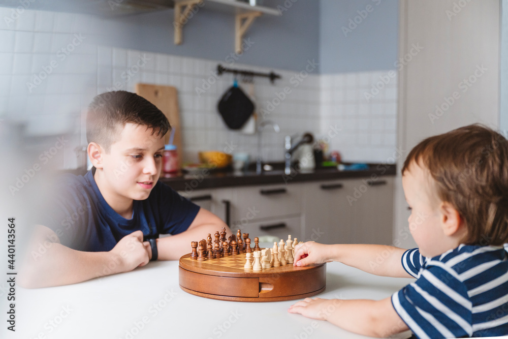 Siblings playing chess at dining table in kitchen at home Stock Photo ...