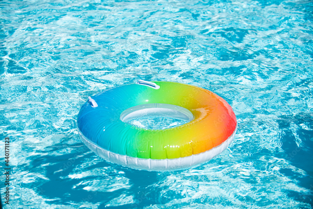 Inflatable ring floating in pool on summer background. Rainbow swimming ...