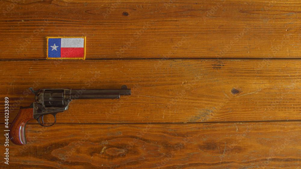 Single action revolver below a Texas state flag patch on a textured ...