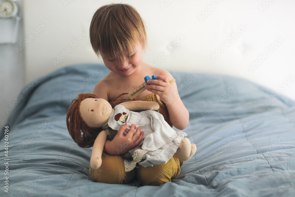 Girl child makes an injection with a wooden syringe to a doll on the ...