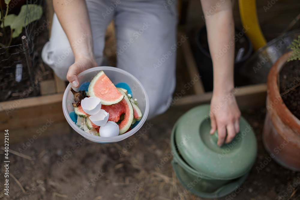 Woman putting food scraps in compost bucket Stock Photo | Adobe Stock
