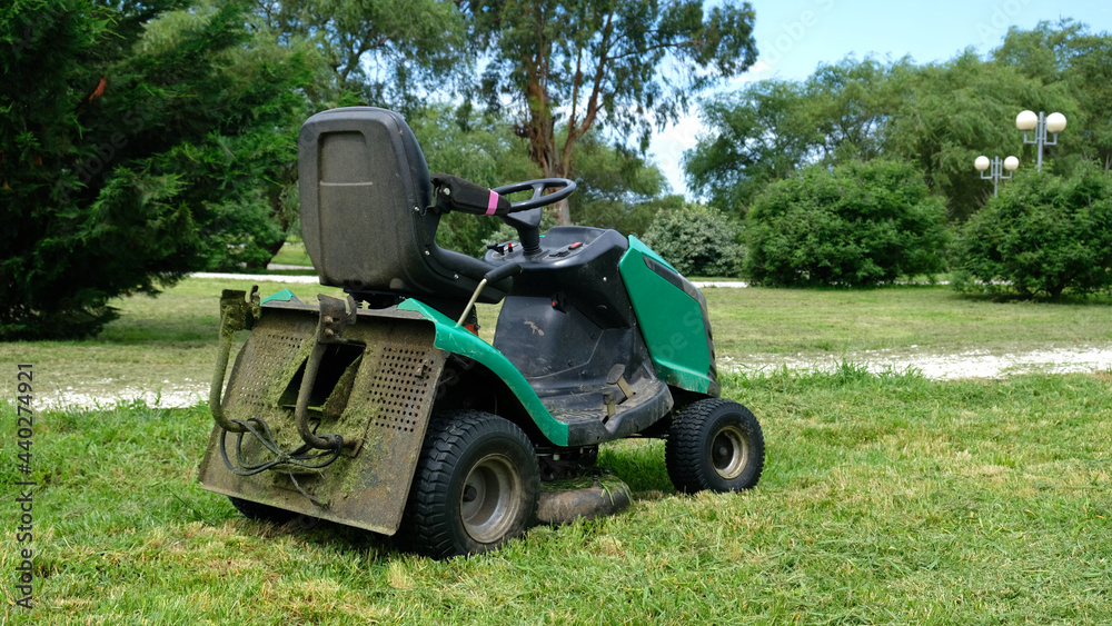Green grass trimming with lawn mower. Tractor mowing grass in a public ...