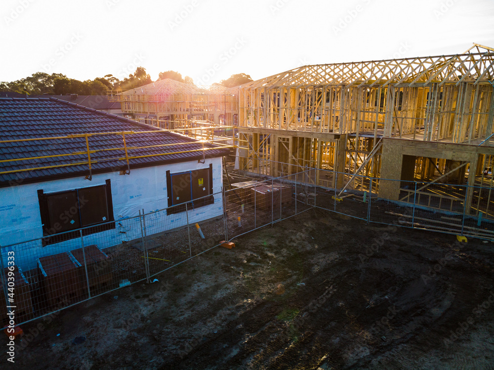 Sunset in the suburbs, houses at different stages of construction sit ...