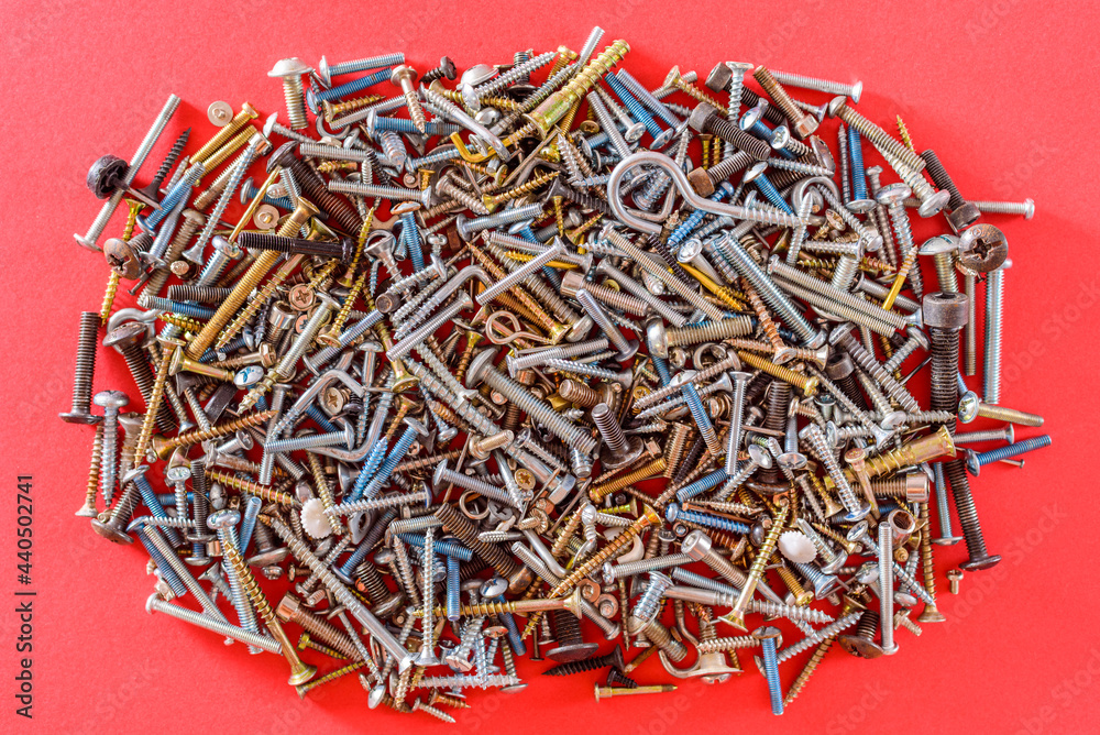 Isolated pile of screws of different types on red color background ...