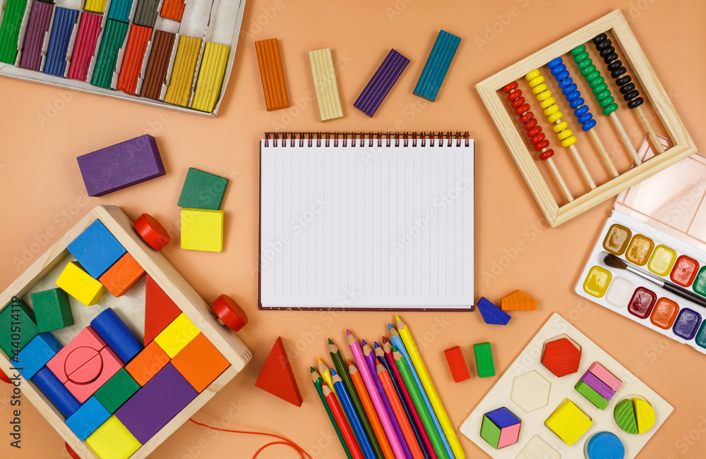 Colorful cubes, paints, pencils, blocks, modeling clay on orange ...